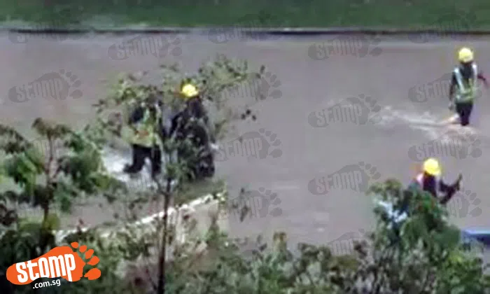Workers wade through shin-deep water after heavy rain causes flood at ...