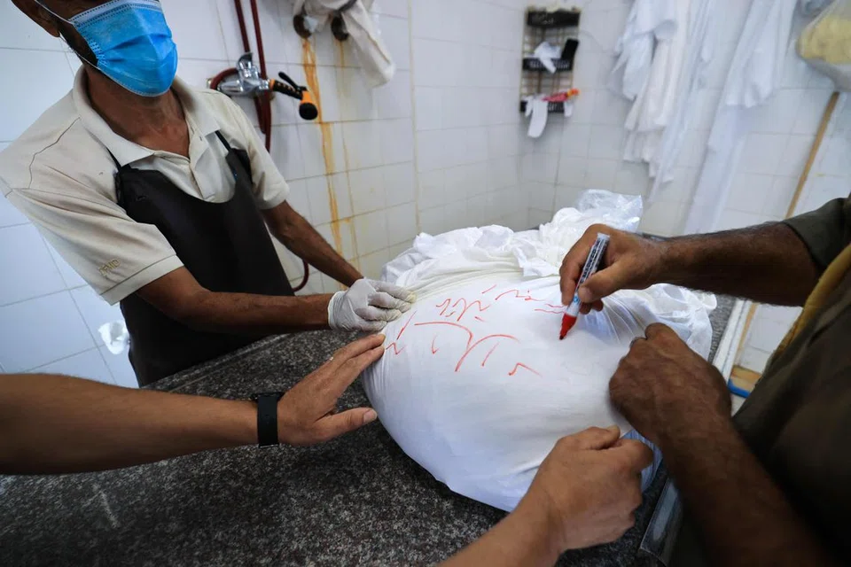 A Palestinian medic marks a shroud for human remains collected ...